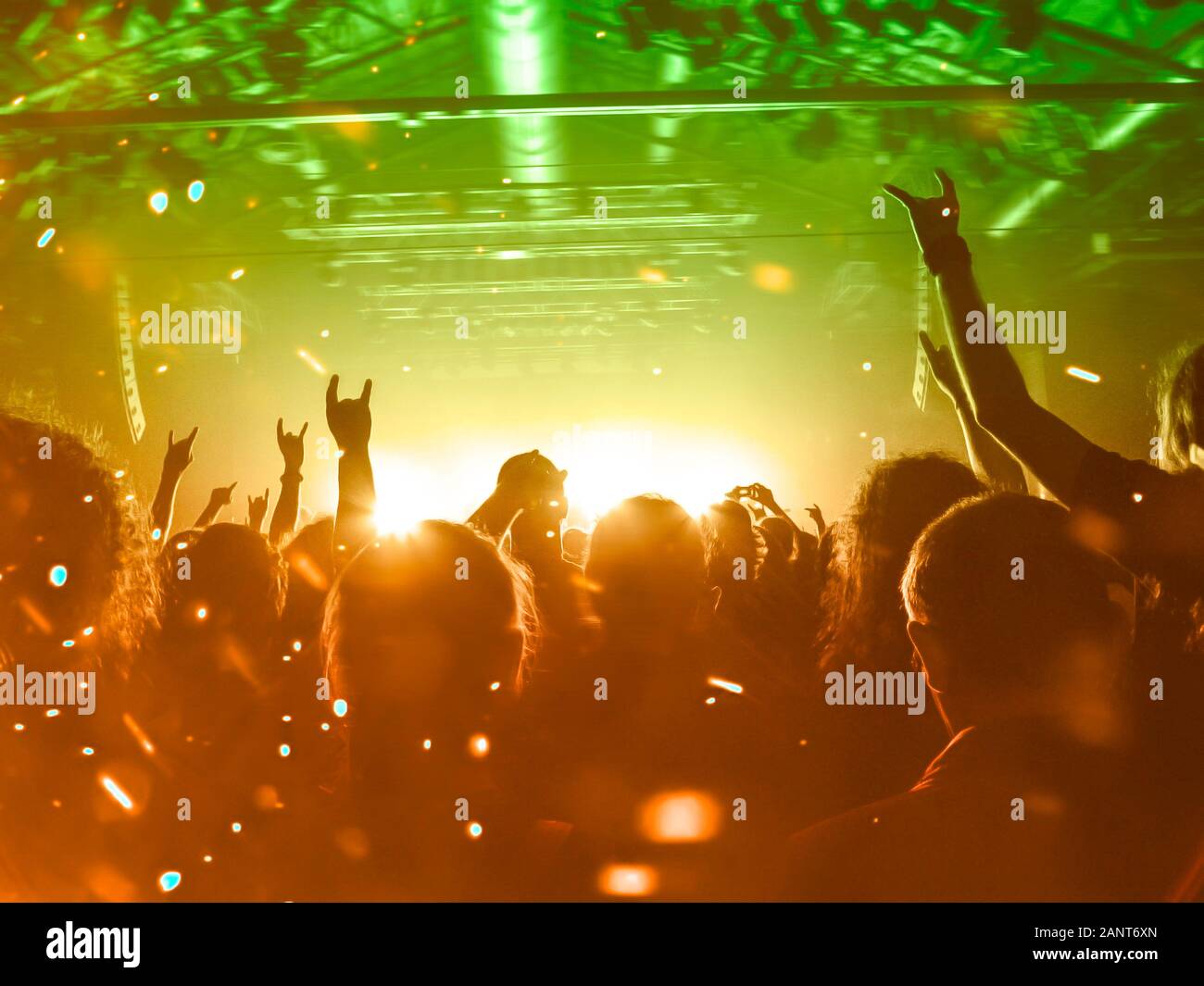 Colourful concert stage inside a venue, people silhouettes are visible ...
