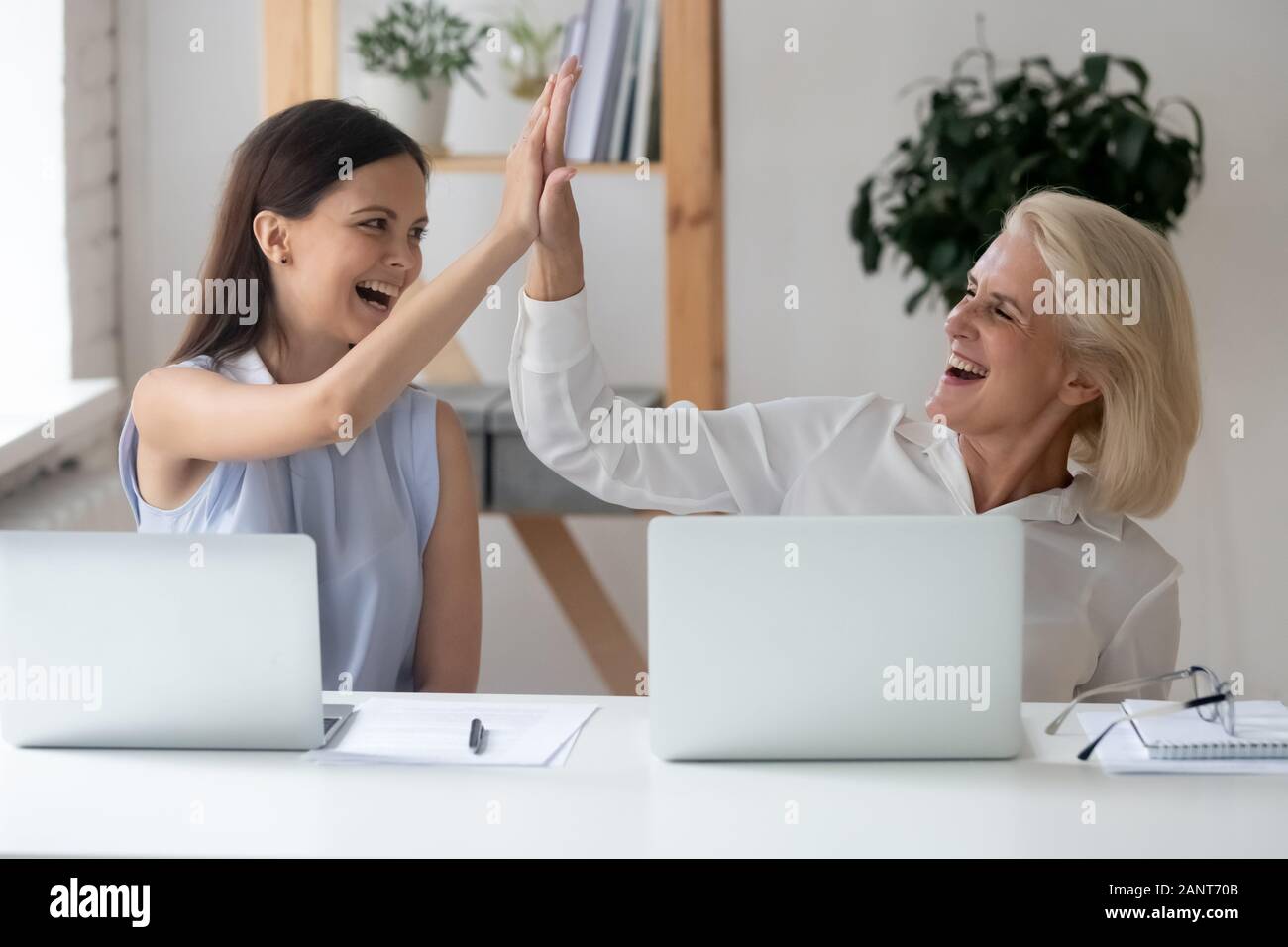 Different generations women colleagues giving high five celebrating ...