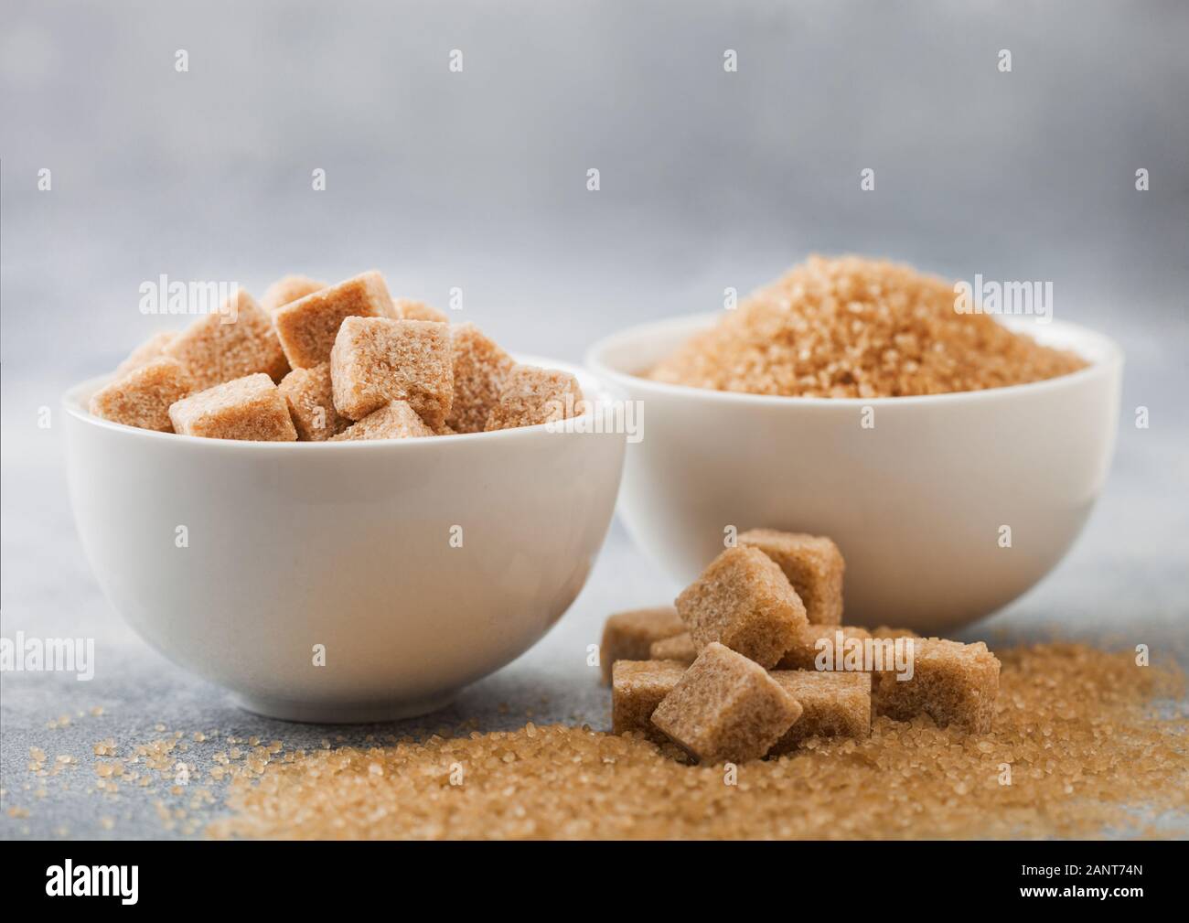 White bowl plates of natural brown sugar cubes and refined sugar on ...