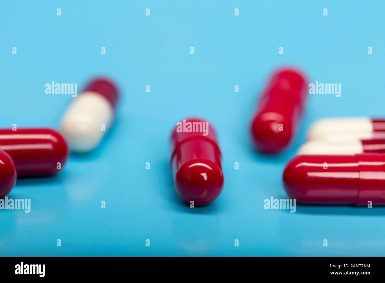 Red-white medicinal capsules on blue background Stock Photo - Alamy
