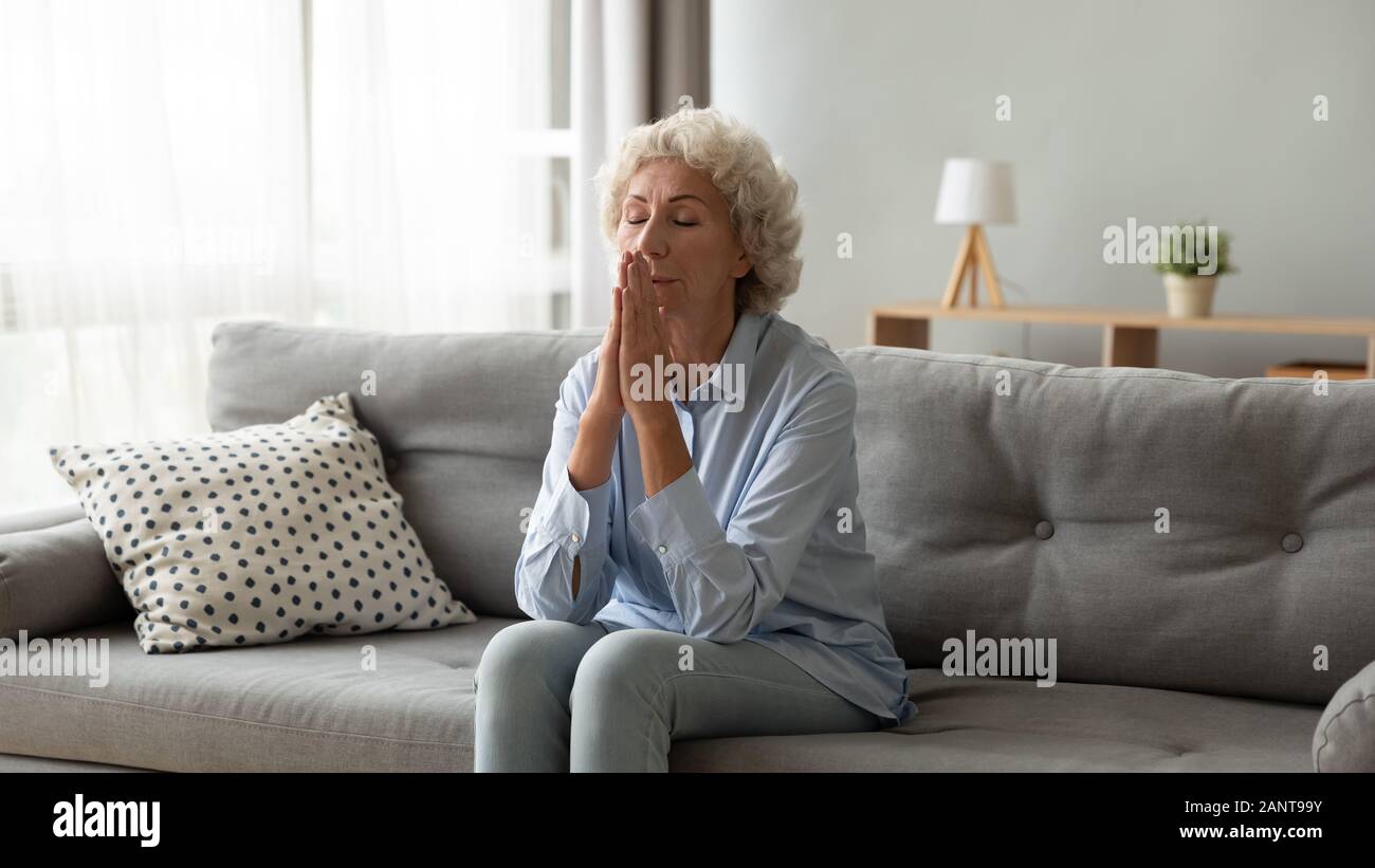 Older woman praying with hope at home, holding hands together Stock ...