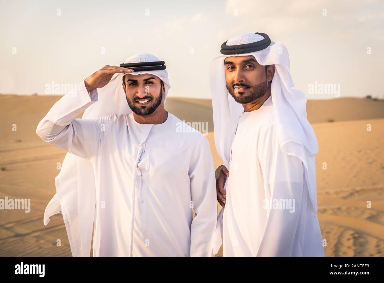 Arabian men witk kandora walking in the desert - Portrait of two middle ...