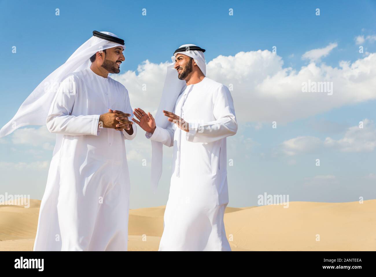 Arabian men witk kandora walking in the desert - Portrait of two middle ...