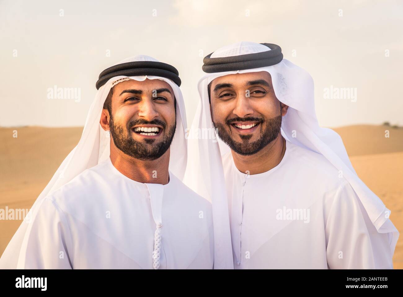Arabian men witk kandora walking in the desert - Portrait of two middle ...