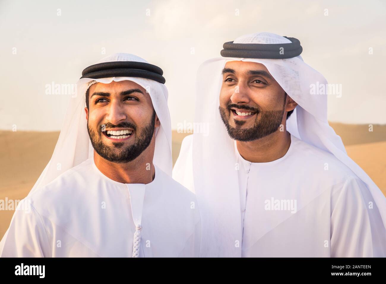 Arabian men witk kandora walking in the desert - Portrait of two middle ...