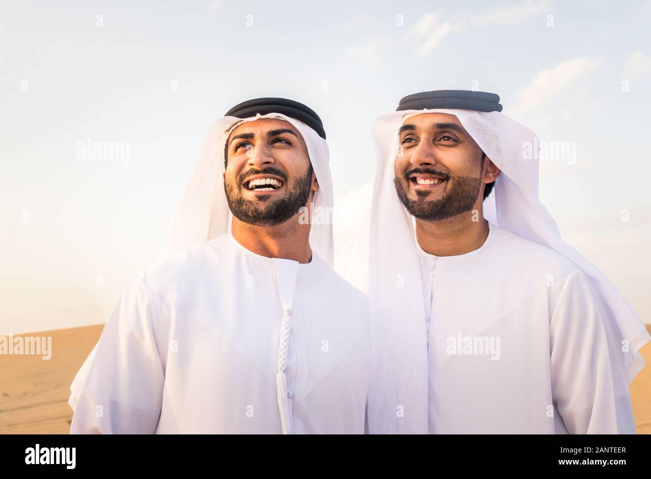 Arabian men witk kandora walking in the desert - Portrait of two middle ...
