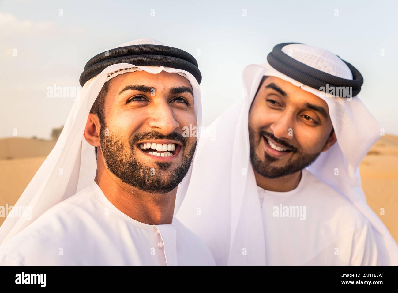 Arabian men witk kandora walking in the desert - Portrait of two middle ...