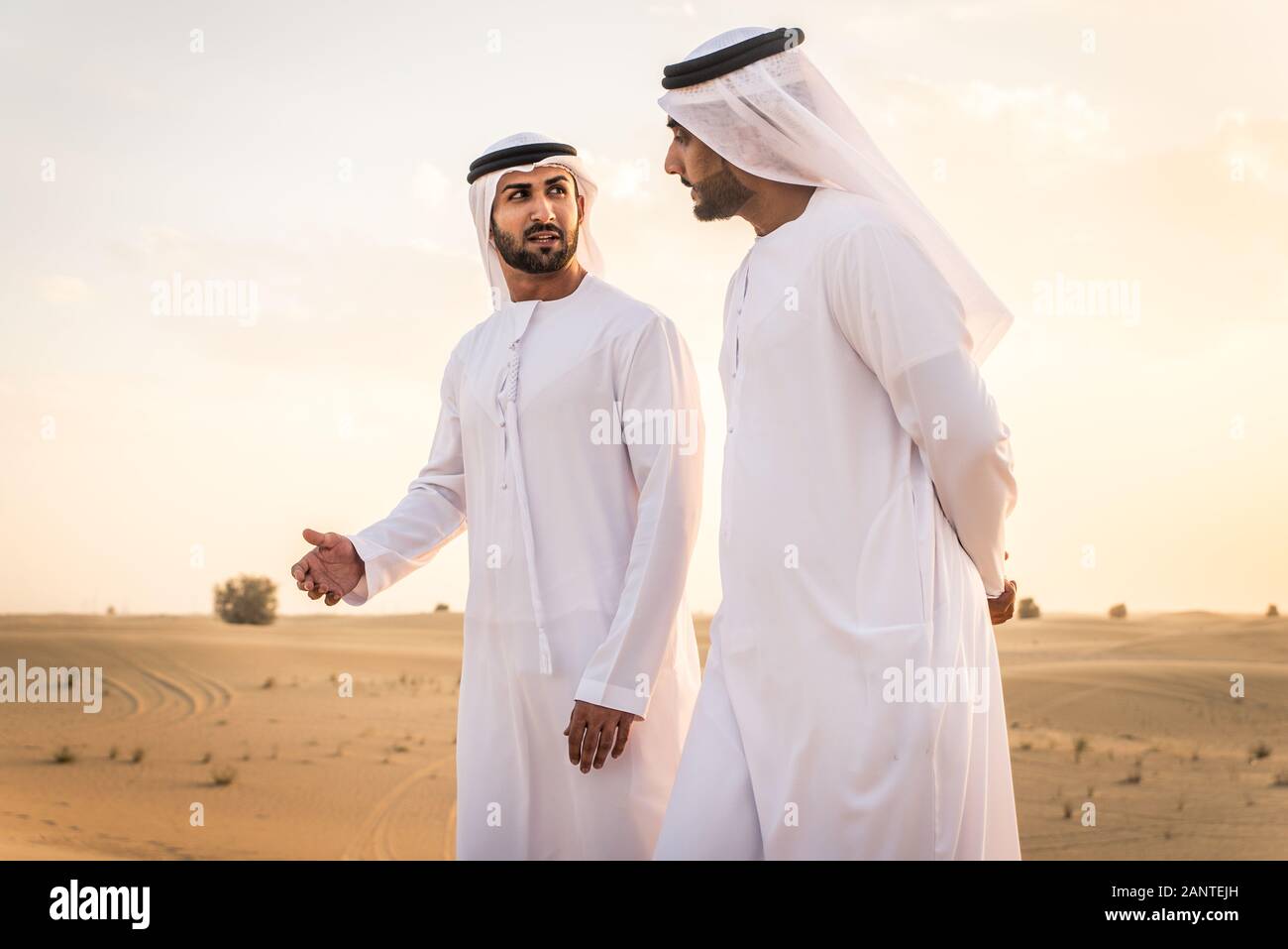 Arabian men witk kandora walking in the desert - Portrait of two middle ...