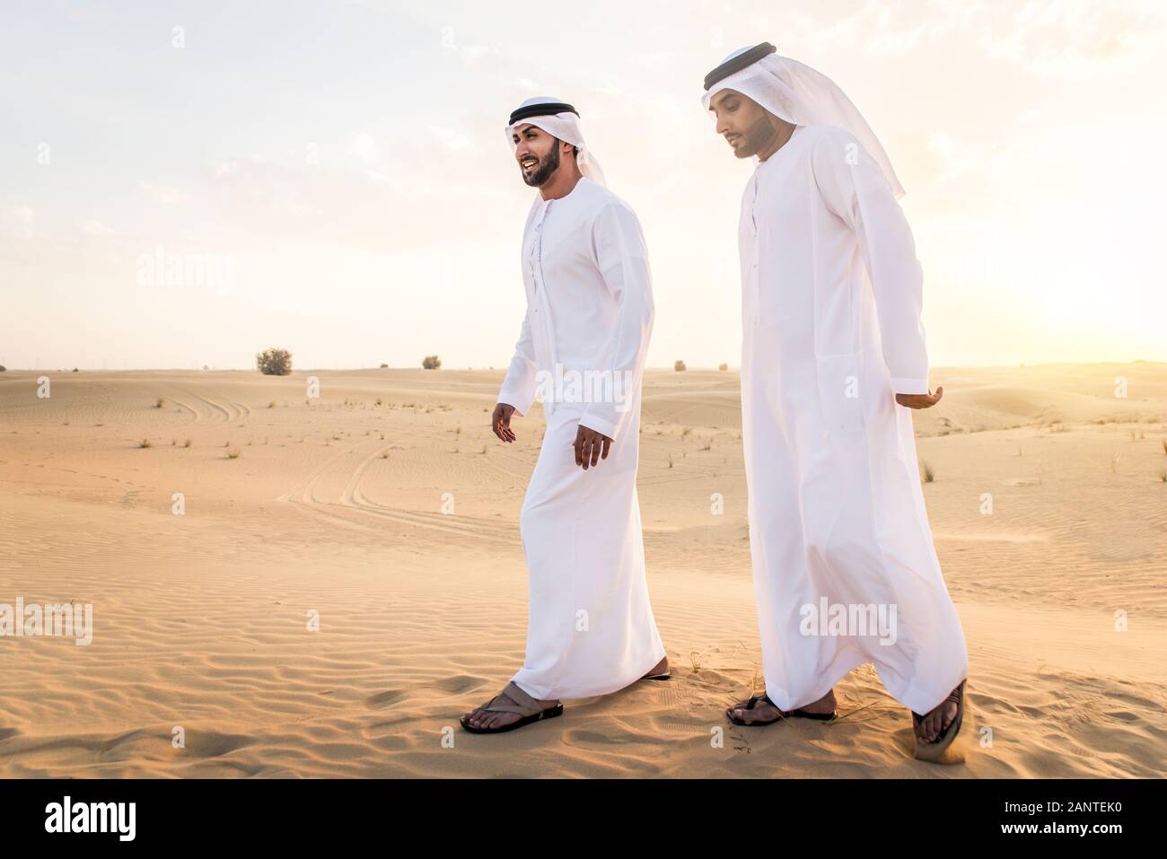 Arabian men witk kandora walking in the desert - Portrait of two middle ...