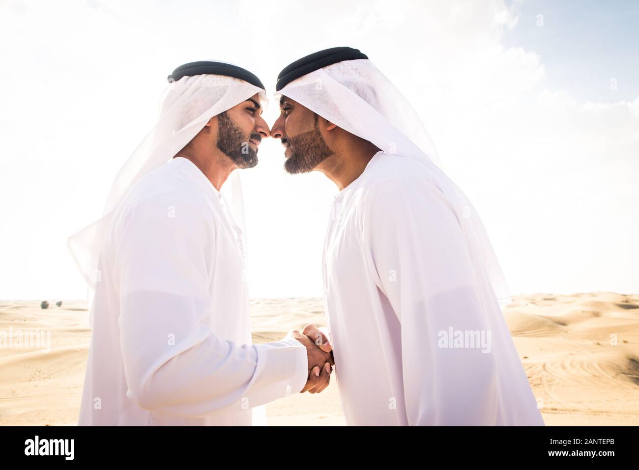 Arabian men witk kandora walking in the desert - Portrait of two middle ...