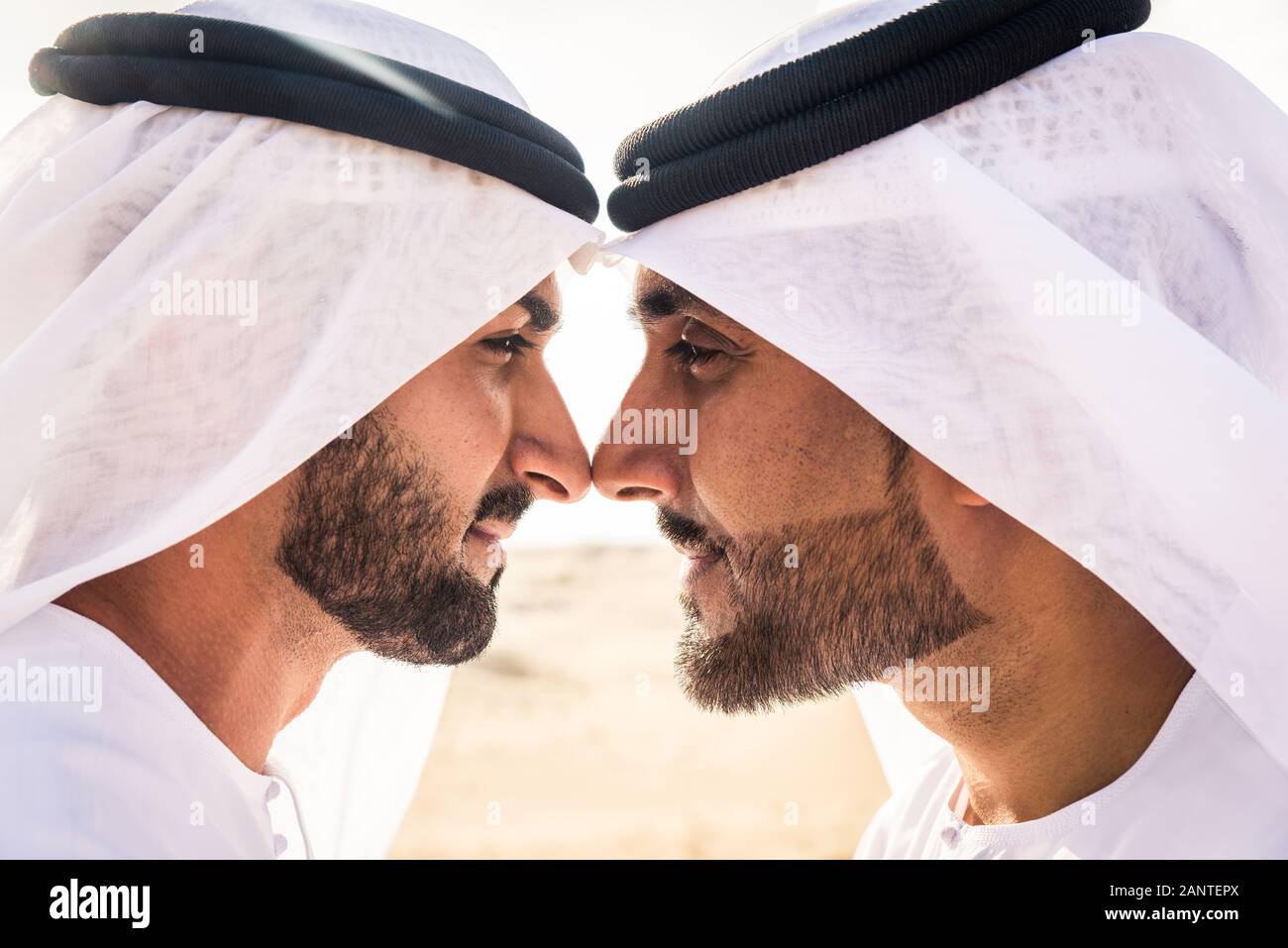 Arabian men witk kandora walking in the desert - Portrait of two middle ...
