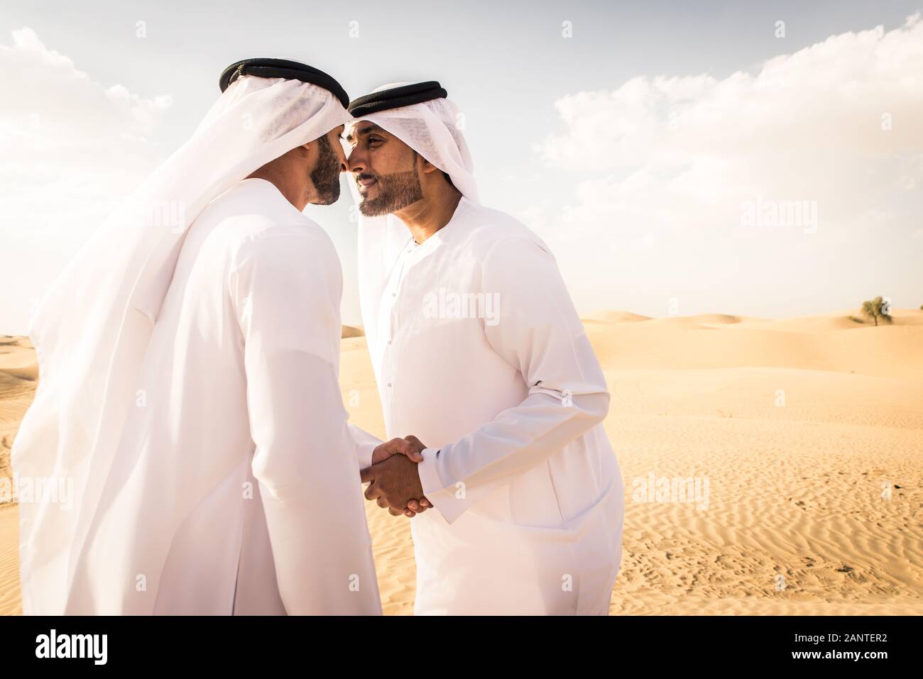 Arabian men witk kandora walking in the desert - Portrait of two middle ...