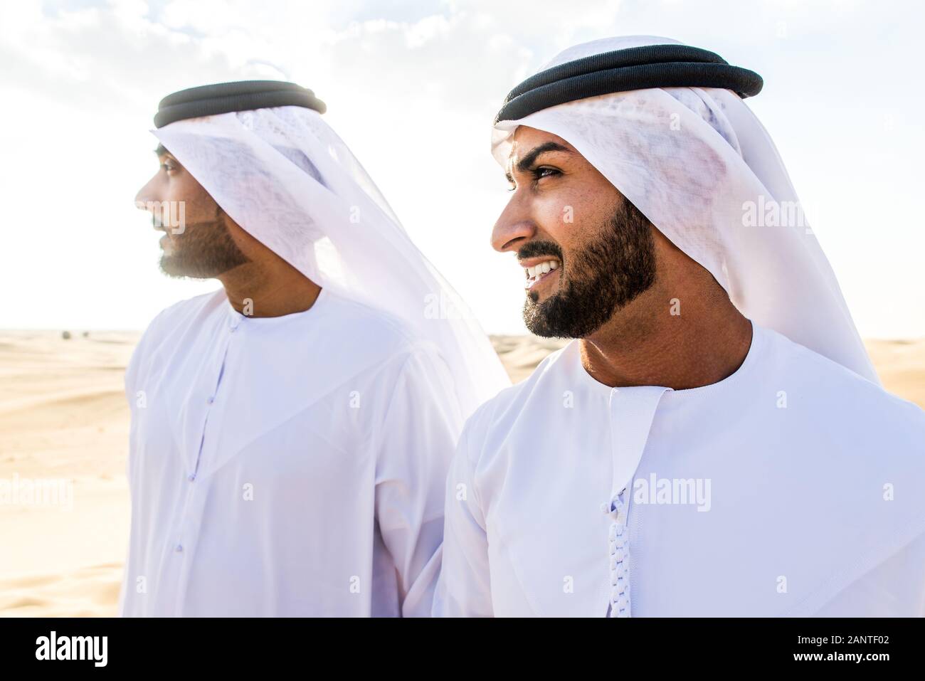 Arabian men witk kandora walking in the desert - Portrait of two middle ...