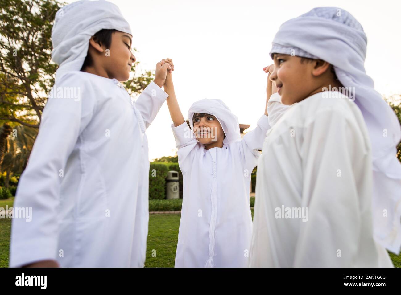 Group of middle-eastern kids wearing white kandora playing in a park in ...