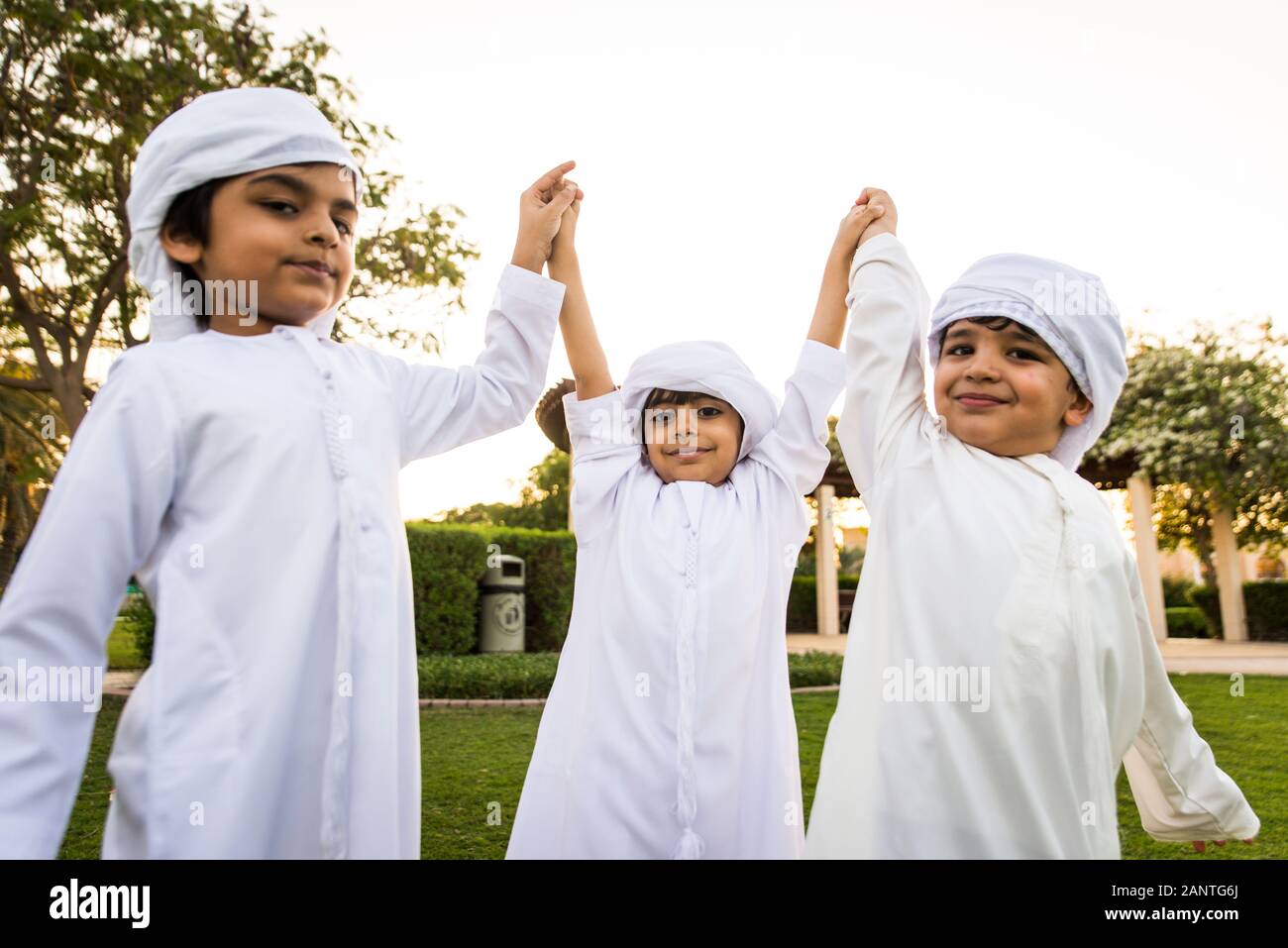 Group of middle-eastern kids wearing white kandora playing in a park in ...
