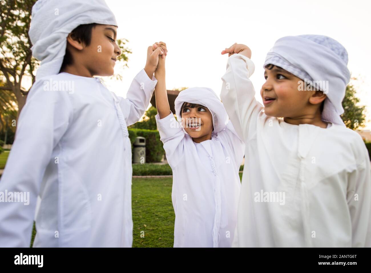 Group of middle-eastern kids wearing white kandora playing in a park in ...
