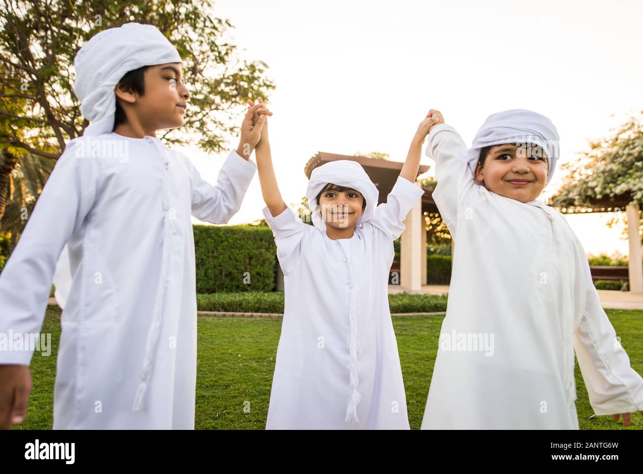 Group of middle-eastern kids wearing white kandora playing in a park in ...