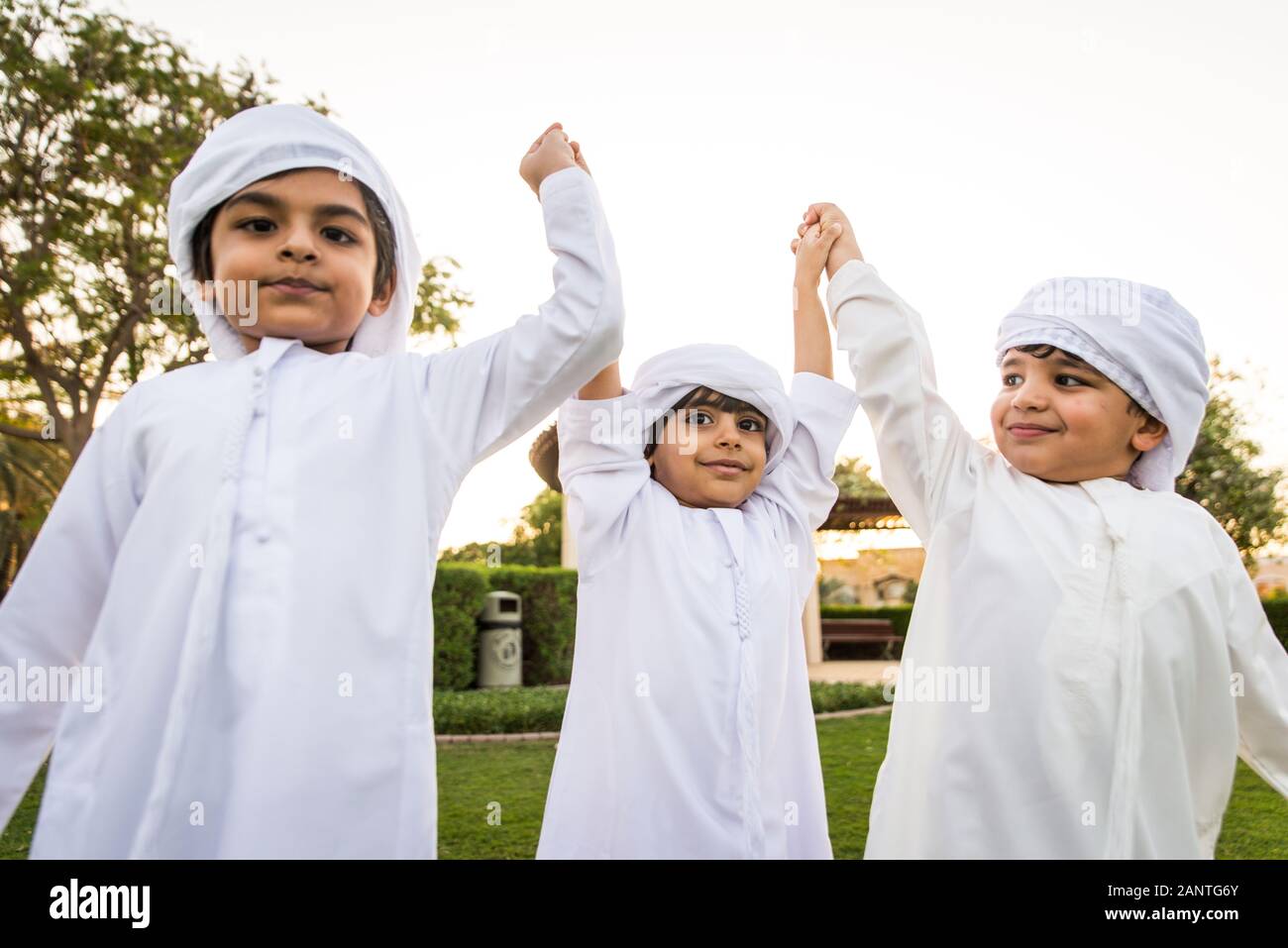 Group of middle-eastern kids wearing white kandora playing in a park in ...
