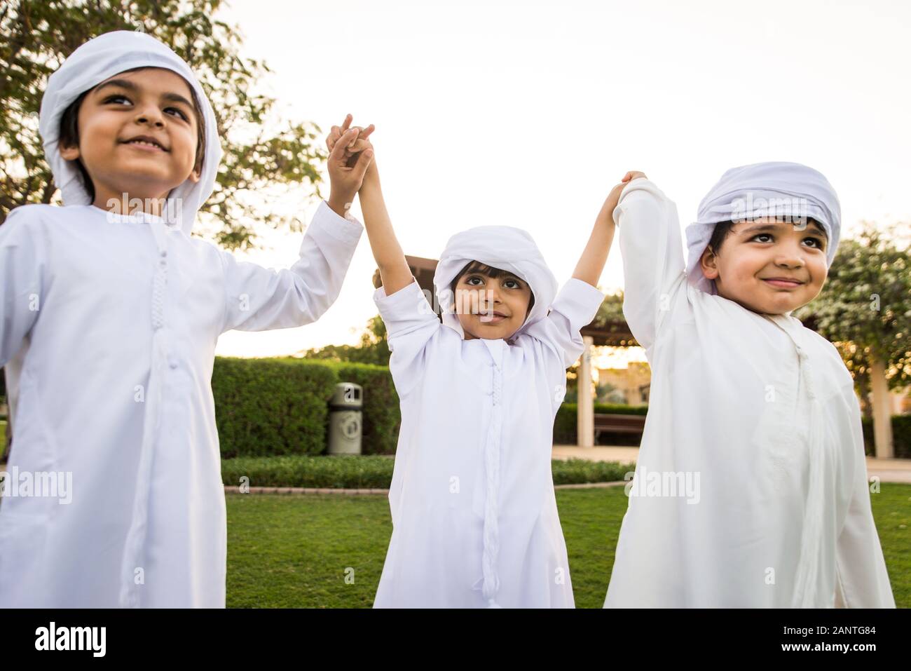 Group of middle-eastern kids wearing white kandora playing in a park in ...