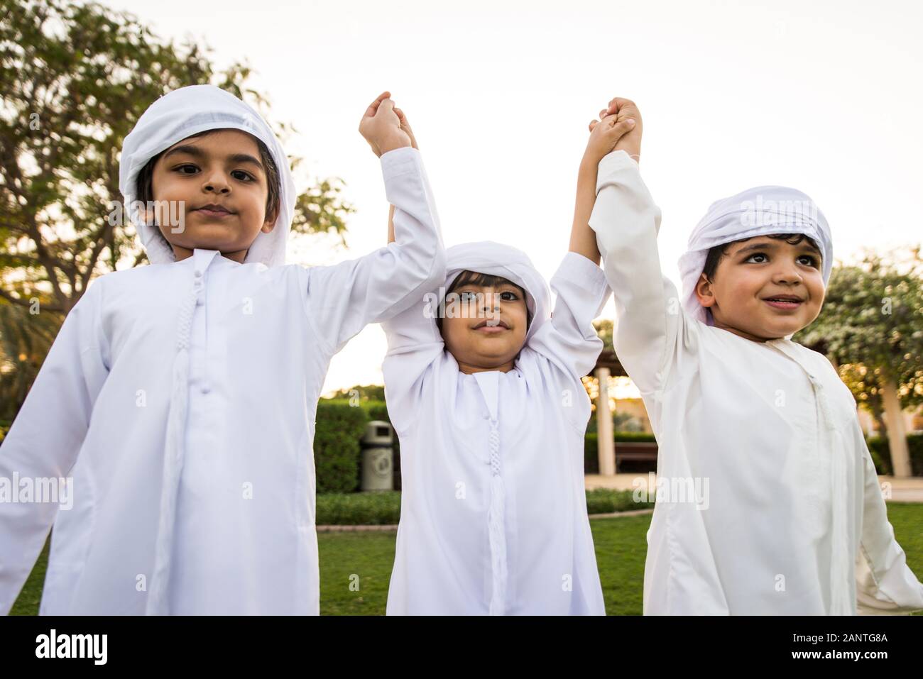 Group of middle-eastern kids wearing white kandora playing in a park in ...