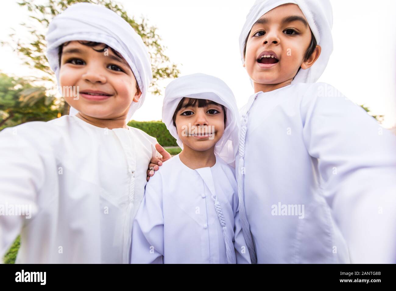 Group of middle-eastern kids wearing white kandora playing in a park in ...