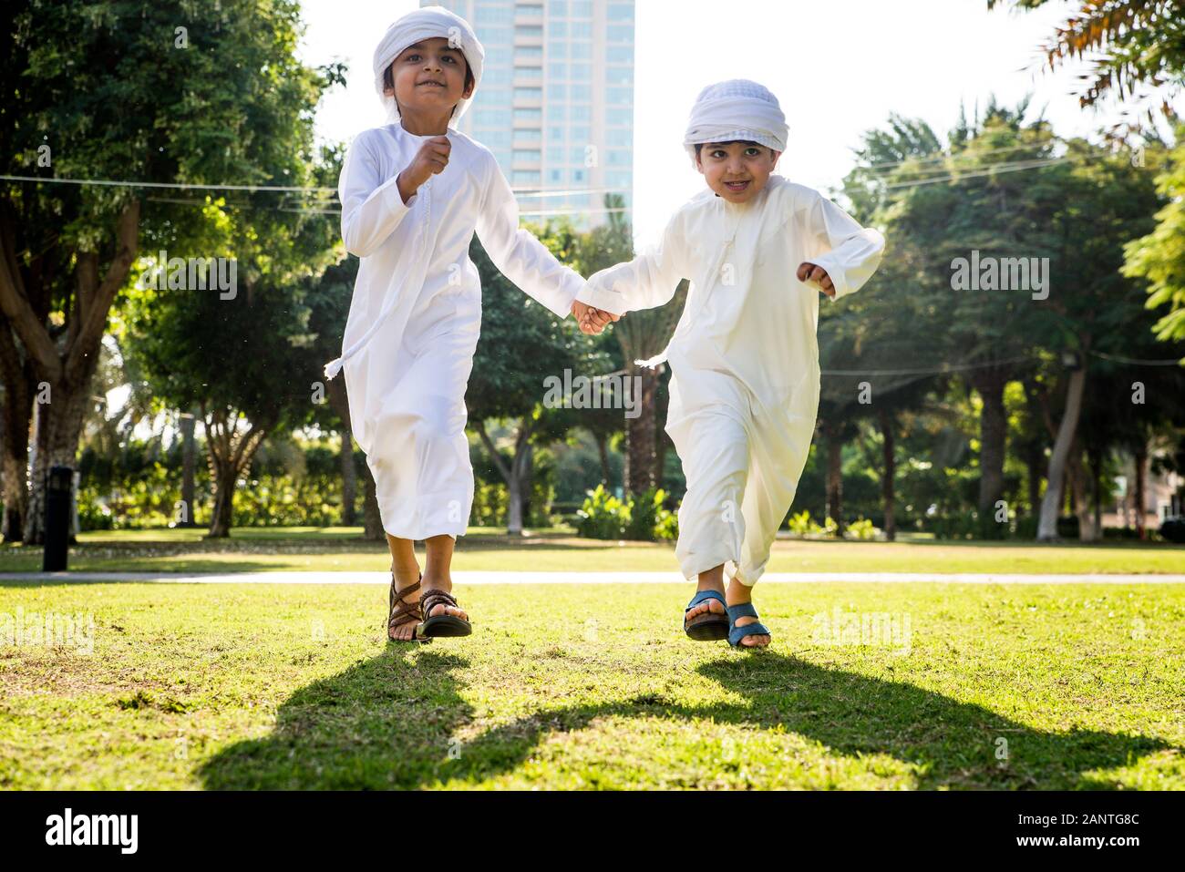 Group of middle-eastern kids wearing white kandora playing in a park in ...