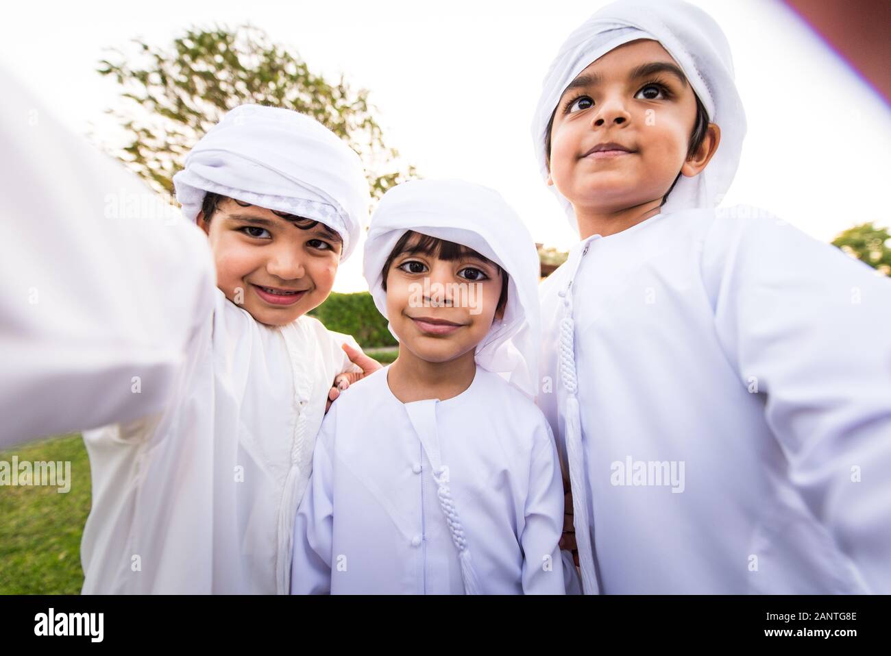 Group of middle-eastern kids wearing white kandora playing in a park in ...