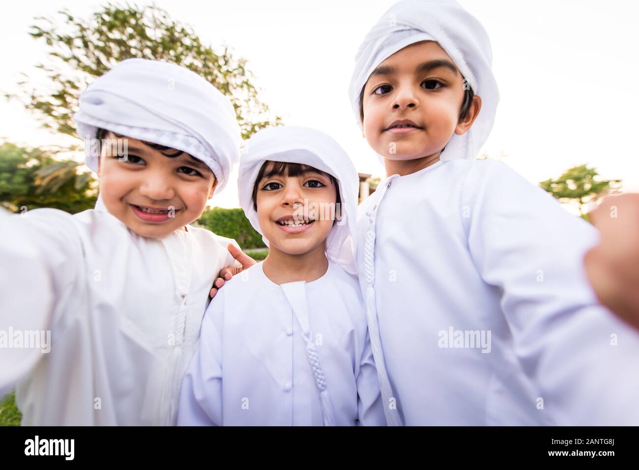 Group of middle-eastern kids wearing white kandora playing in a park in ...