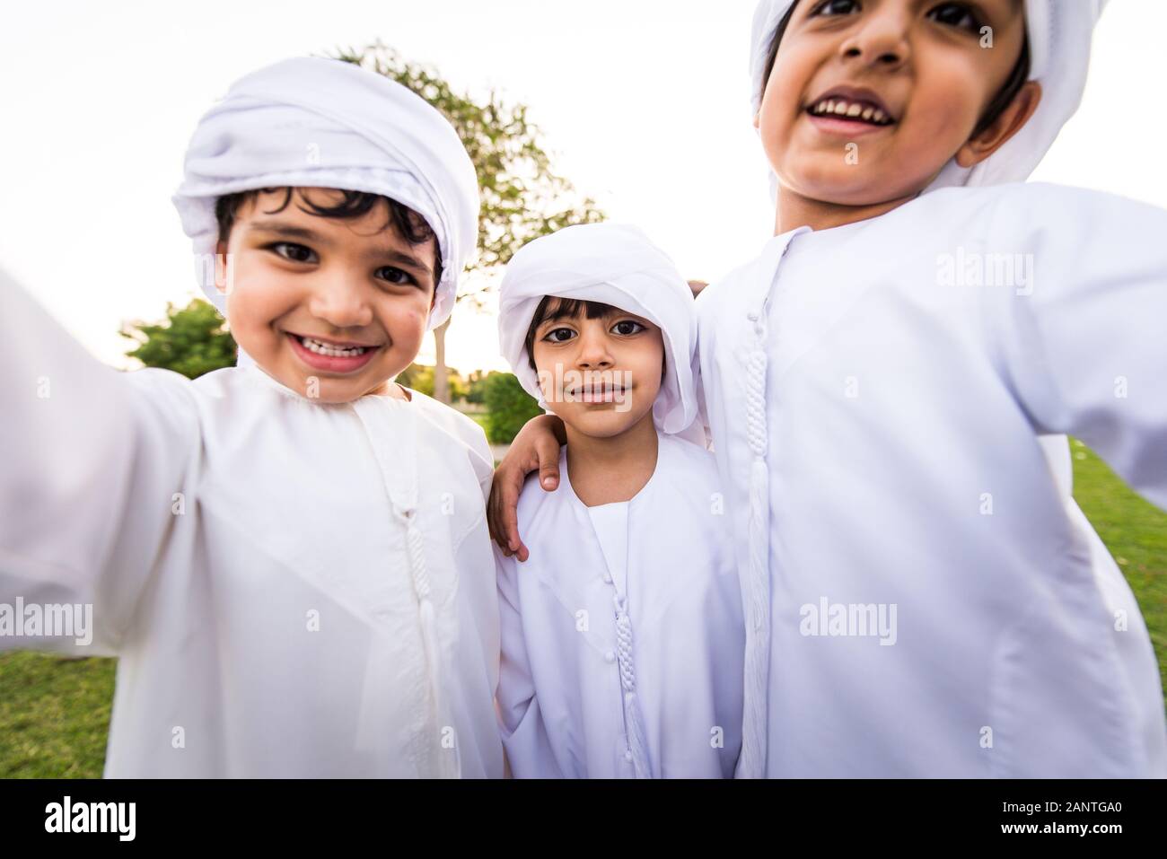 Group of middle-eastern kids wearing white kandora playing in a park in ...
