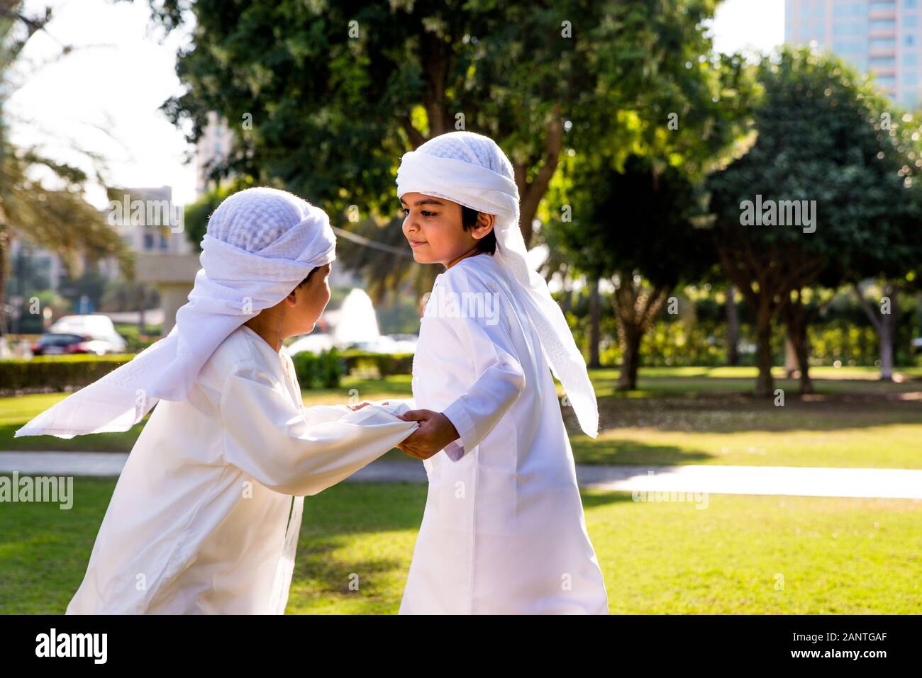 Group of middle-eastern kids wearing white kandora playing in a park in ...