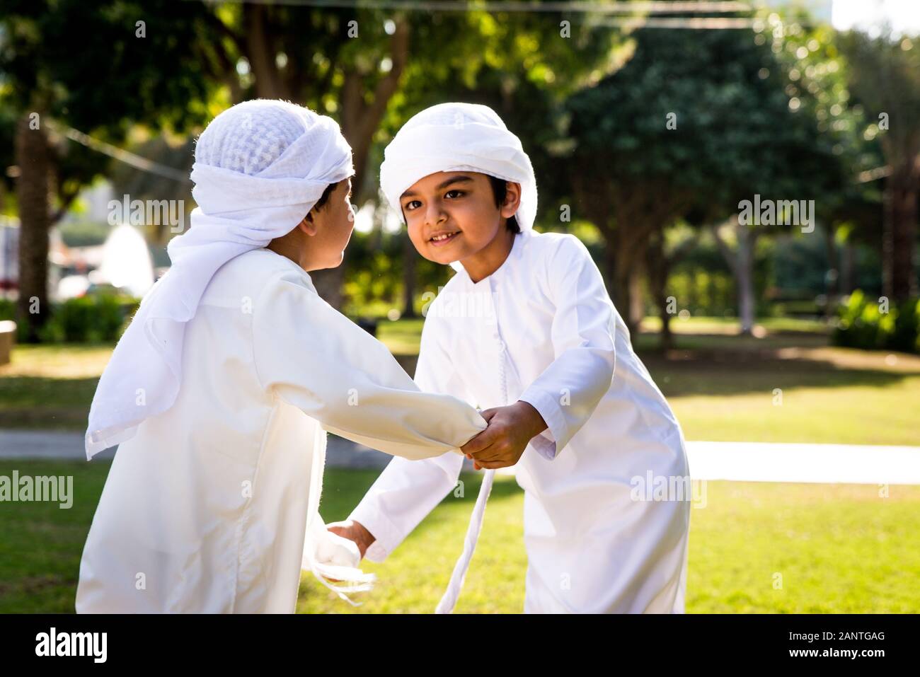 Group of middle-eastern kids wearing white kandora playing in a park in ...