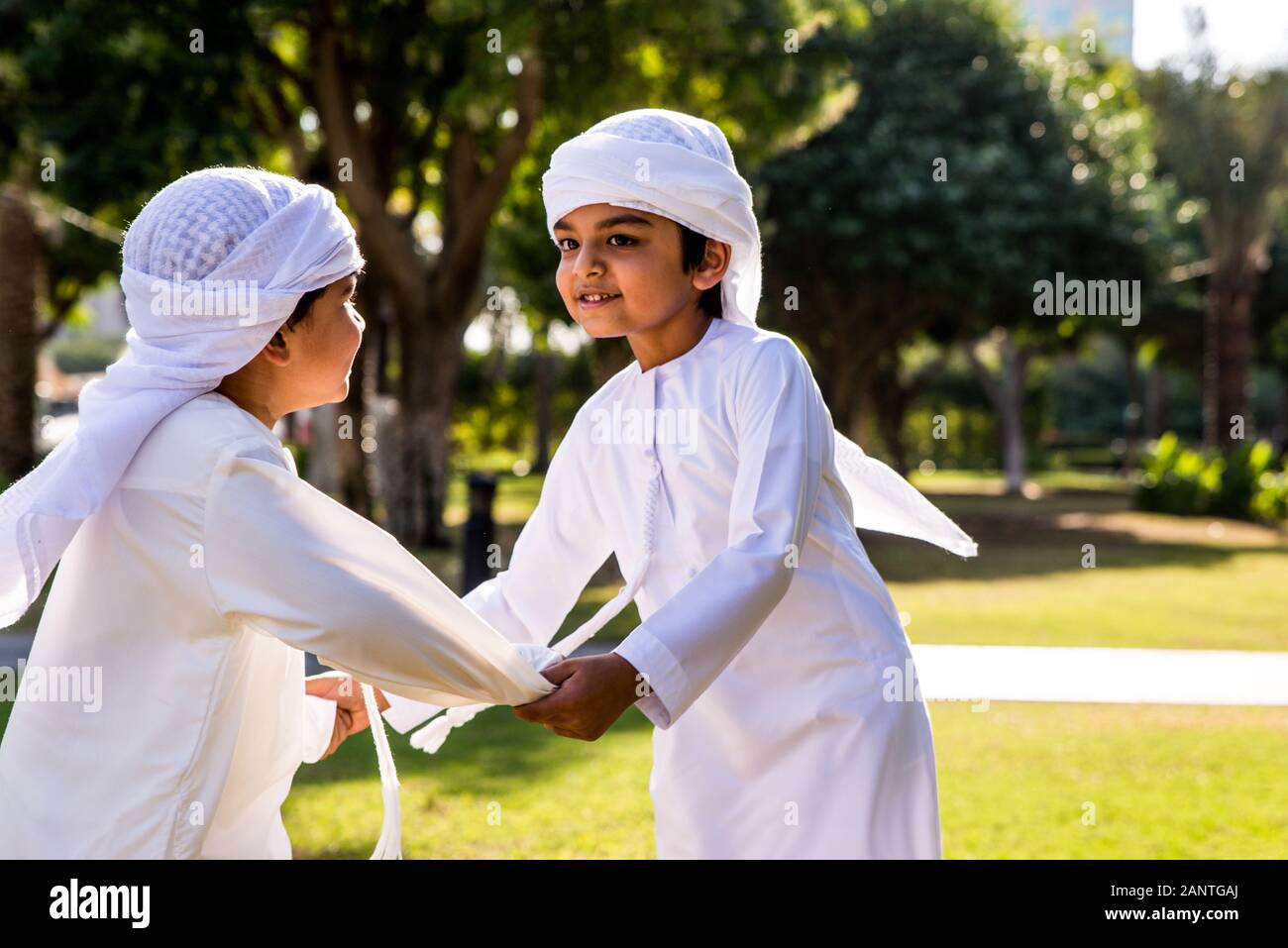 Group of middle-eastern kids wearing white kandora playing in a park in ...