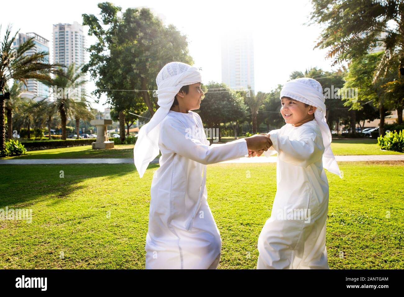 Group of middle-eastern kids wearing white kandora playing in a park in ...