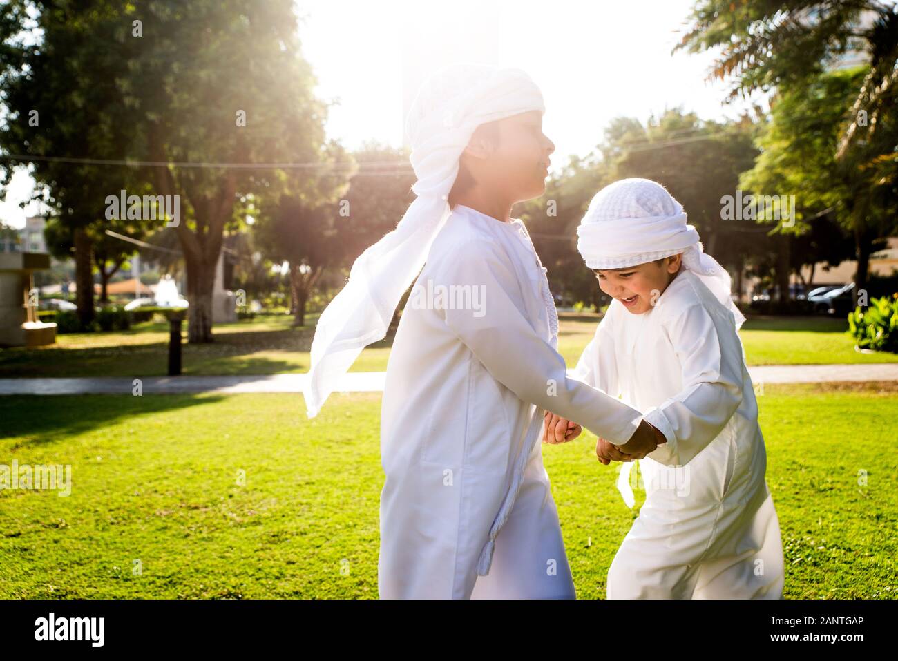 Group of middle-eastern kids wearing white kandora playing in a park in ...