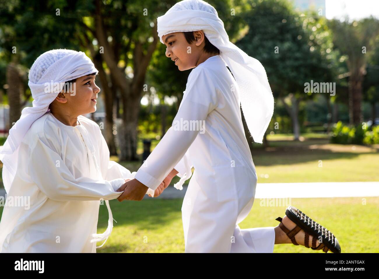 Group of middle-eastern kids wearing white kandora playing in a park in ...