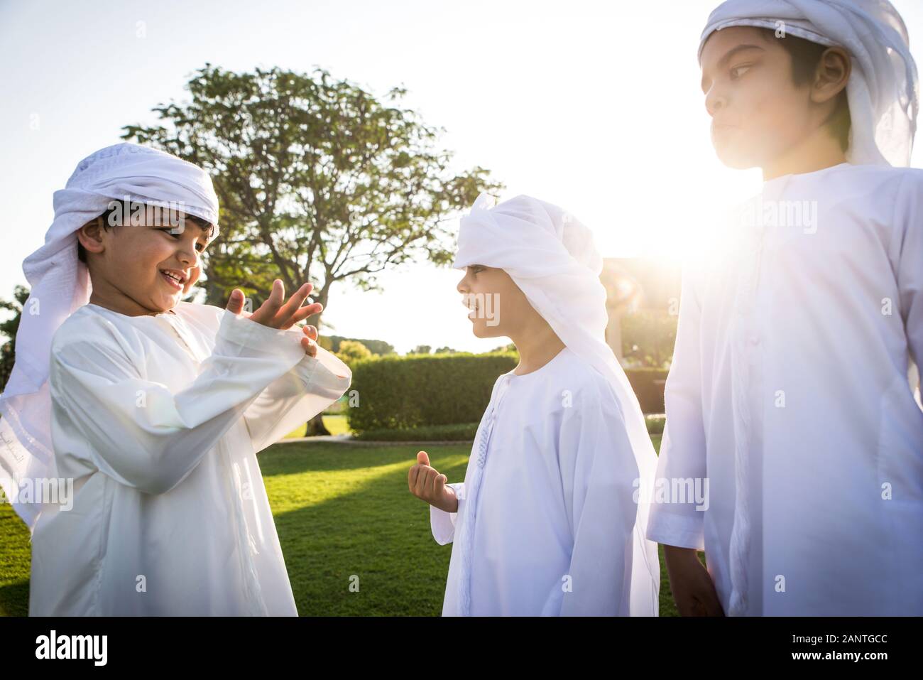 Group of middle-eastern kids wearing white kandora playing in a park in ...