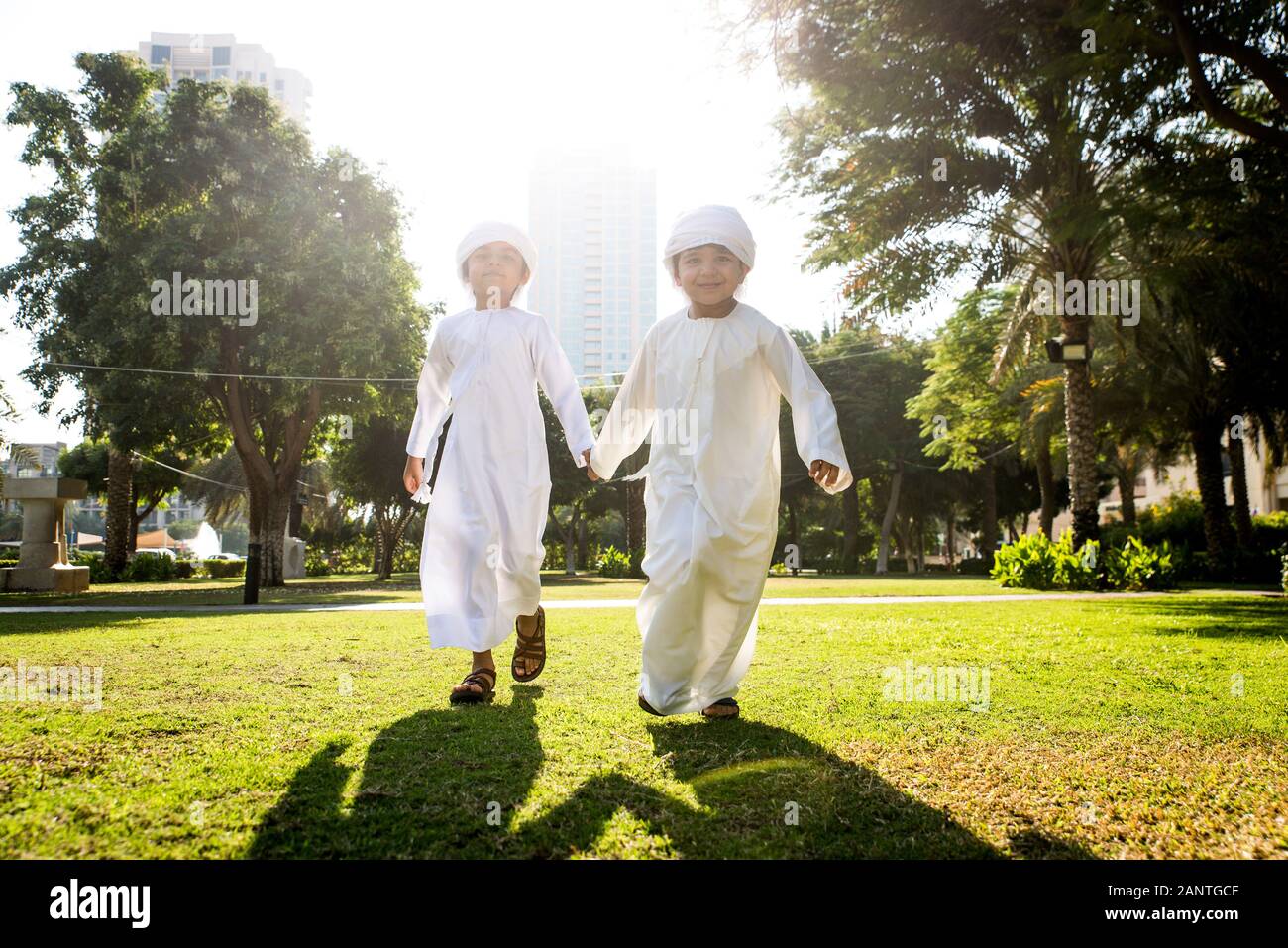 Group of middle-eastern kids wearing white kandora playing in a park in ...