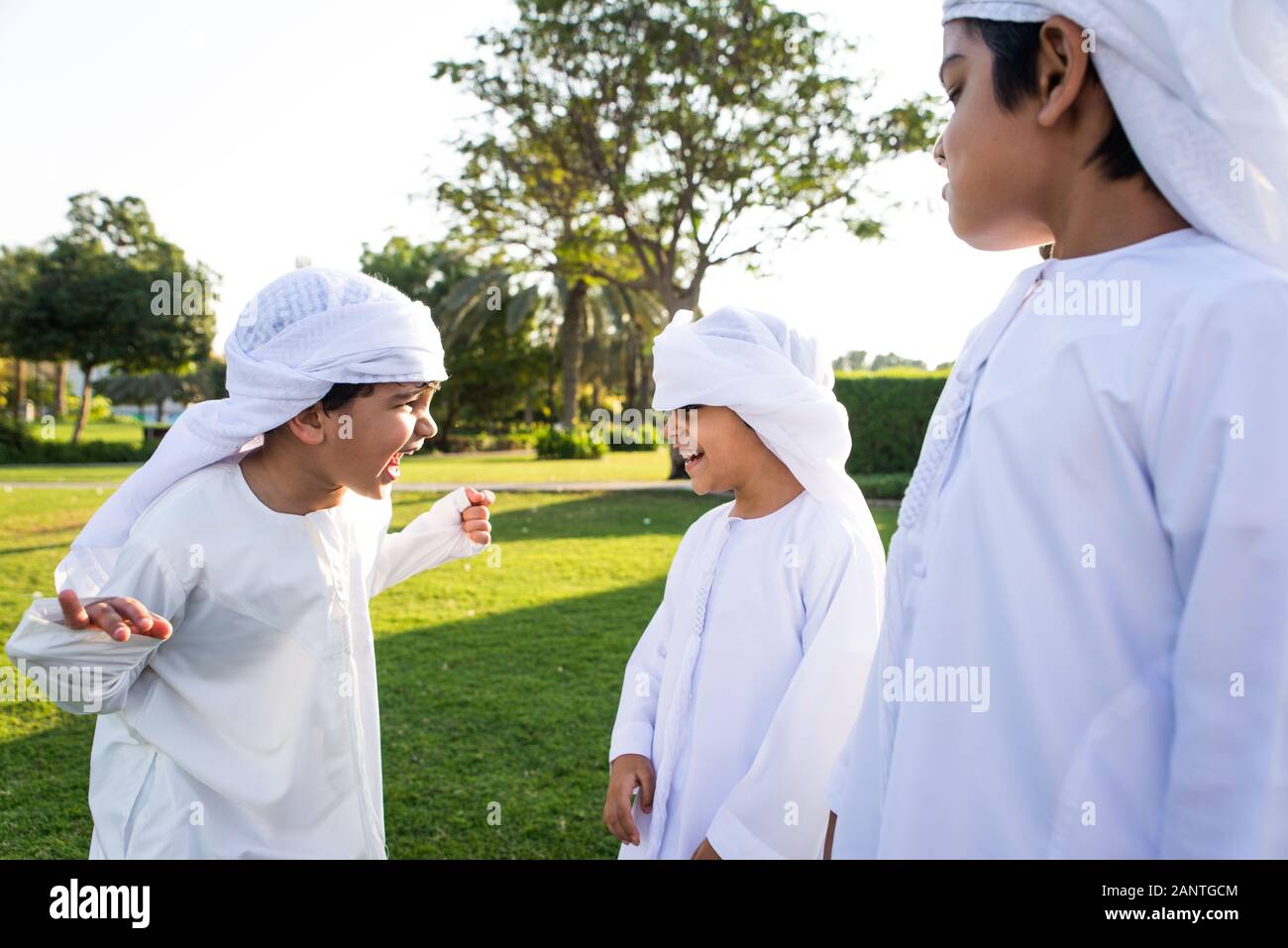 Group of middle-eastern kids wearing white kandora playing in a park in ...