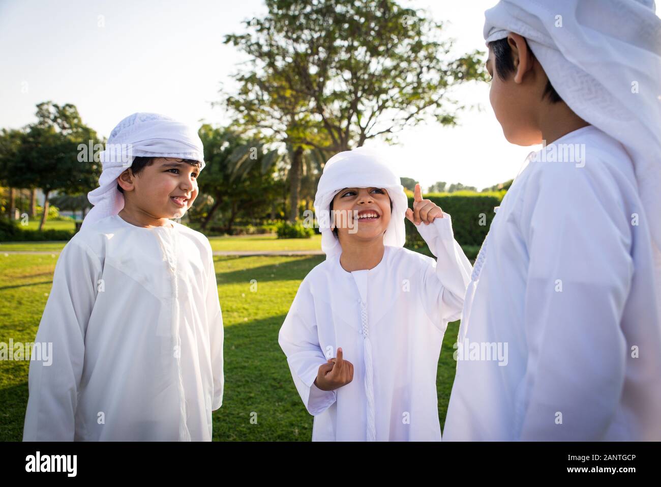 Group of middle-eastern kids wearing white kandora playing in a park in ...