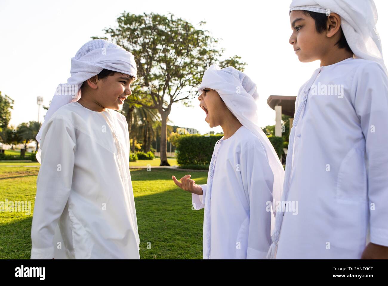 Group of middle-eastern kids wearing white kandora playing in a park in ...