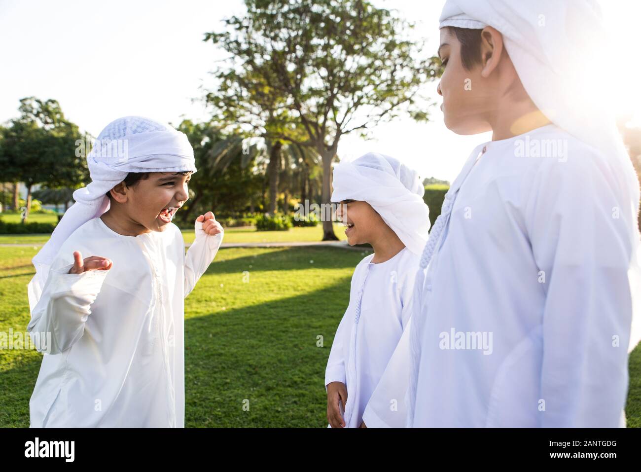 Group of middle-eastern kids wearing white kandora playing in a park in ...
