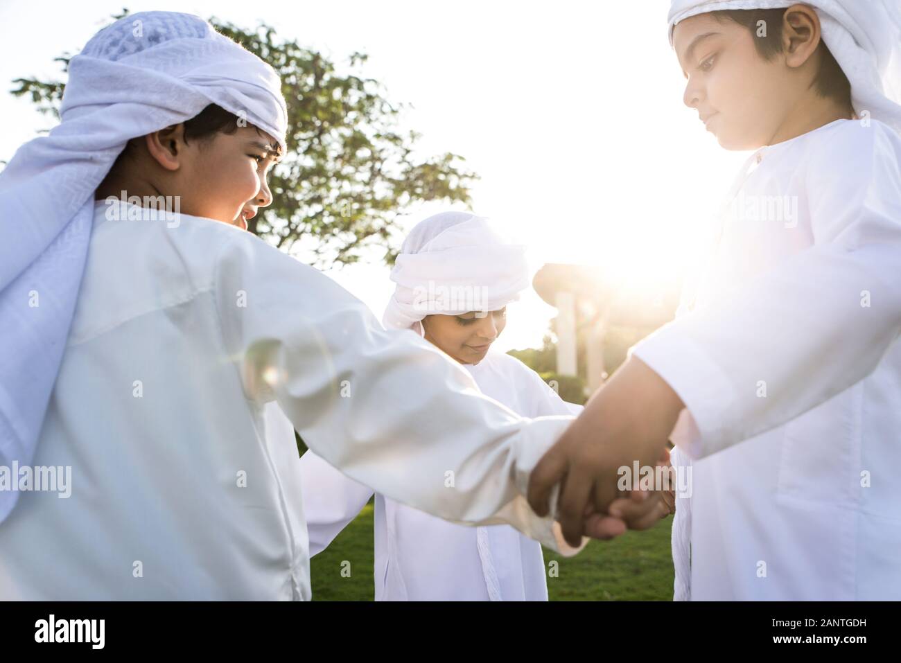 Group of middle-eastern kids wearing white kandora playing in a park in ...