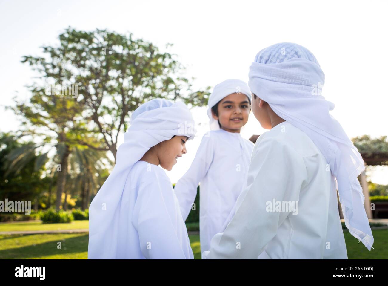 Group of middle-eastern kids wearing white kandora playing in a park in ...