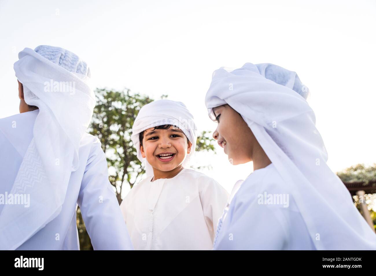 Group of middle-eastern kids wearing white kandora playing in a park in ...