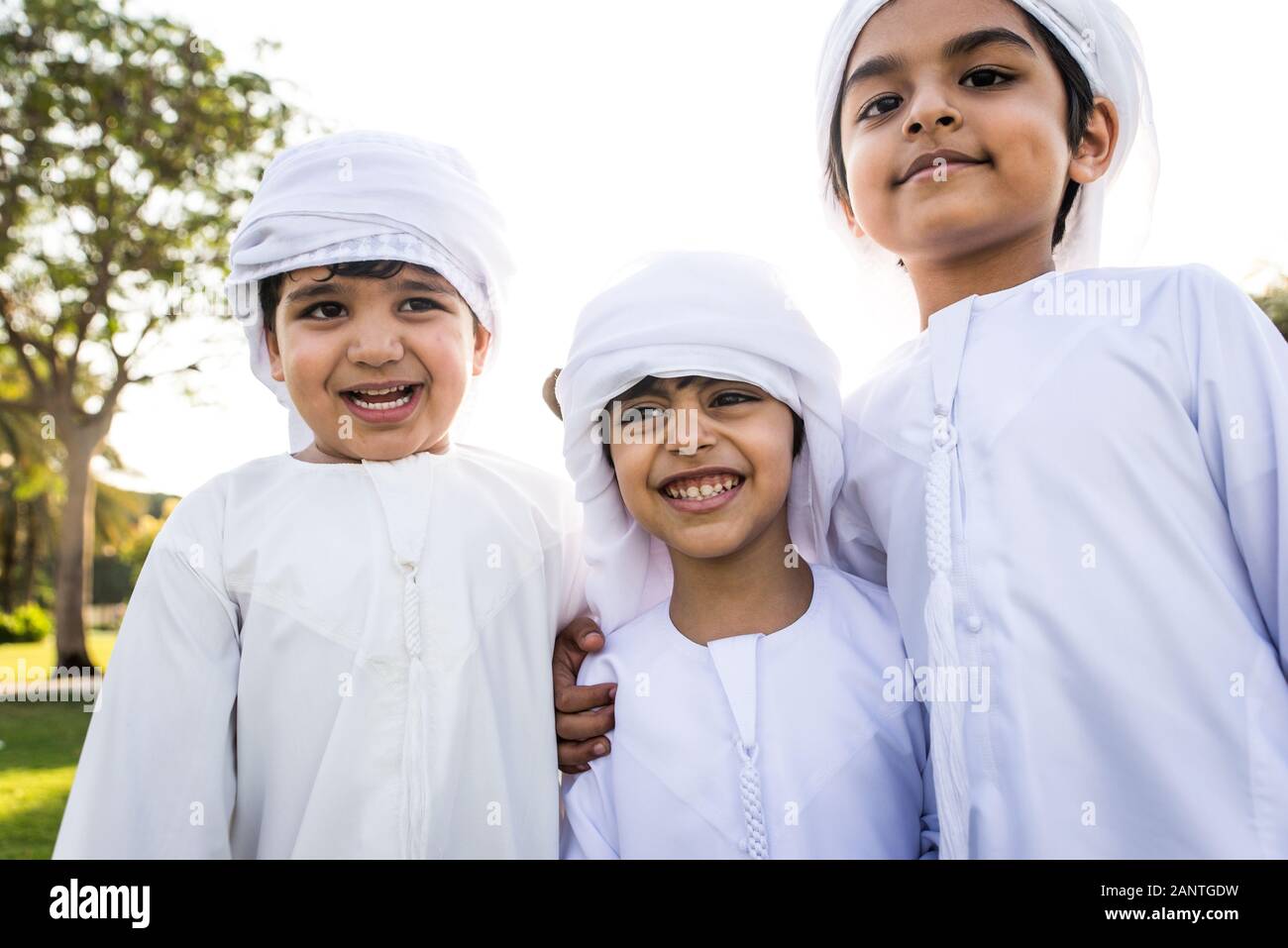 Group of middle-eastern kids wearing white kandora playing in a park in ...