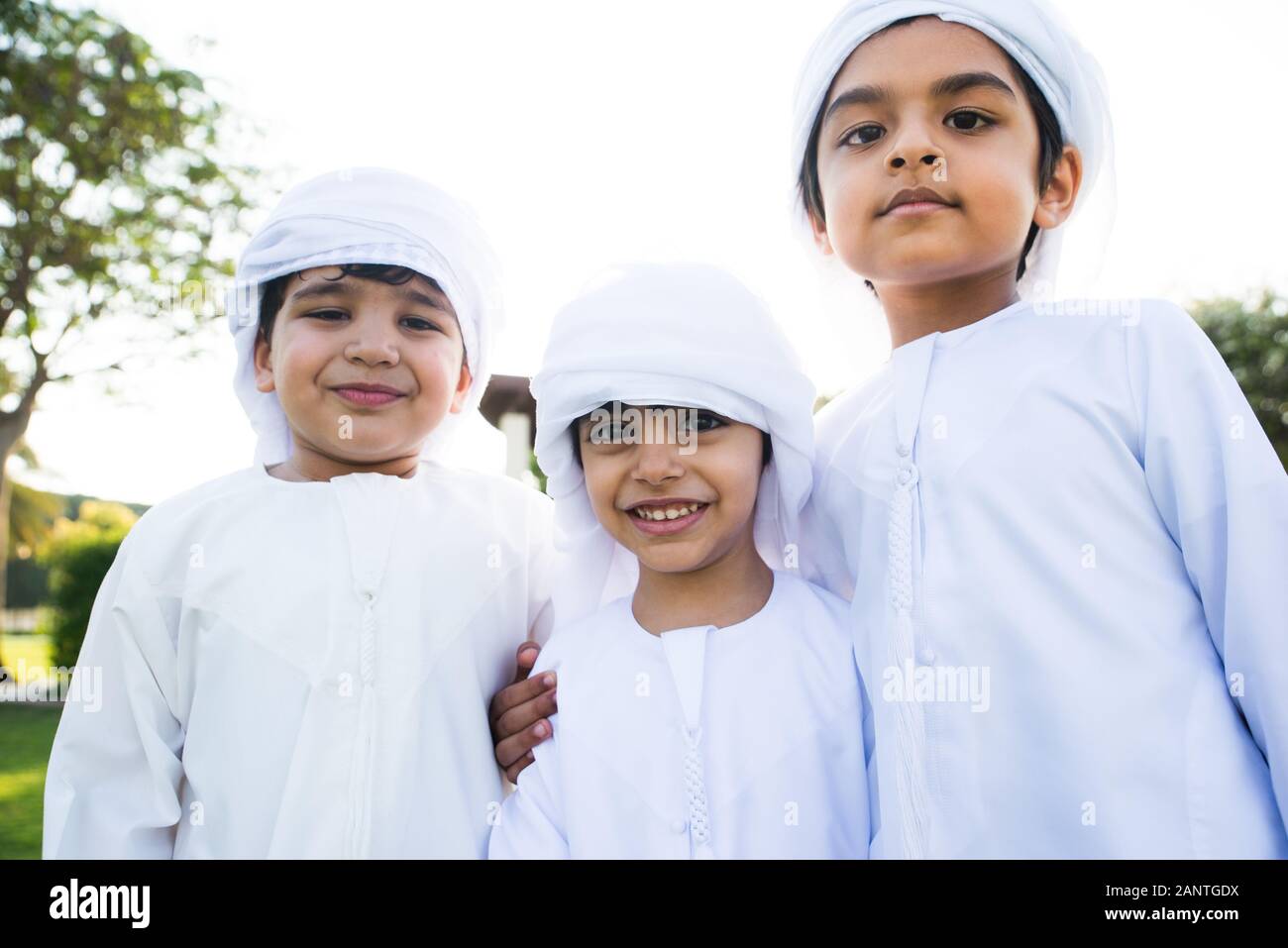 Group of middle-eastern kids wearing white kandora playing in a park in ...