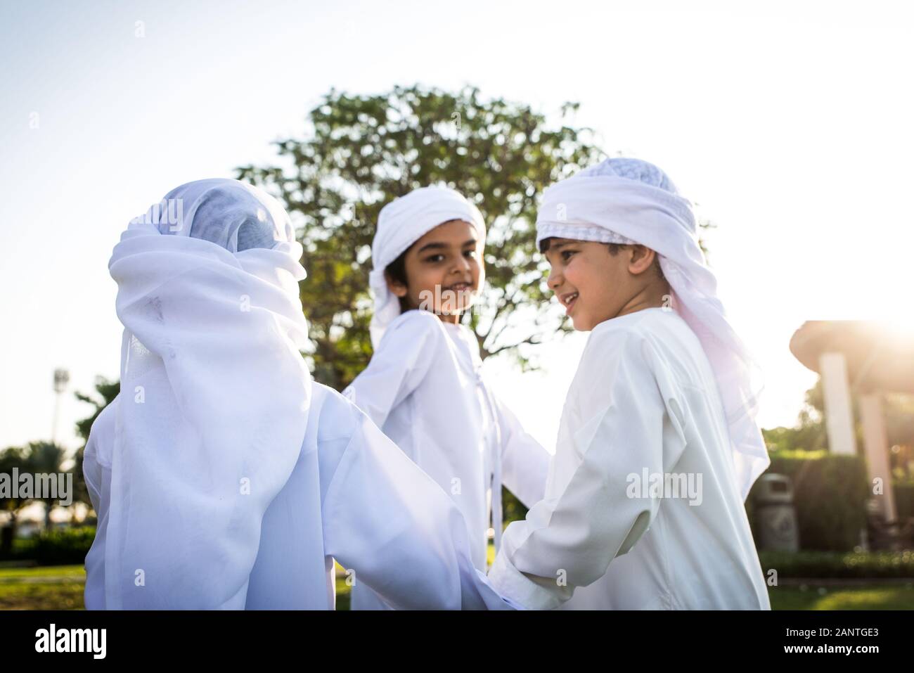 Group of middle-eastern kids wearing white kandora playing in a park in ...