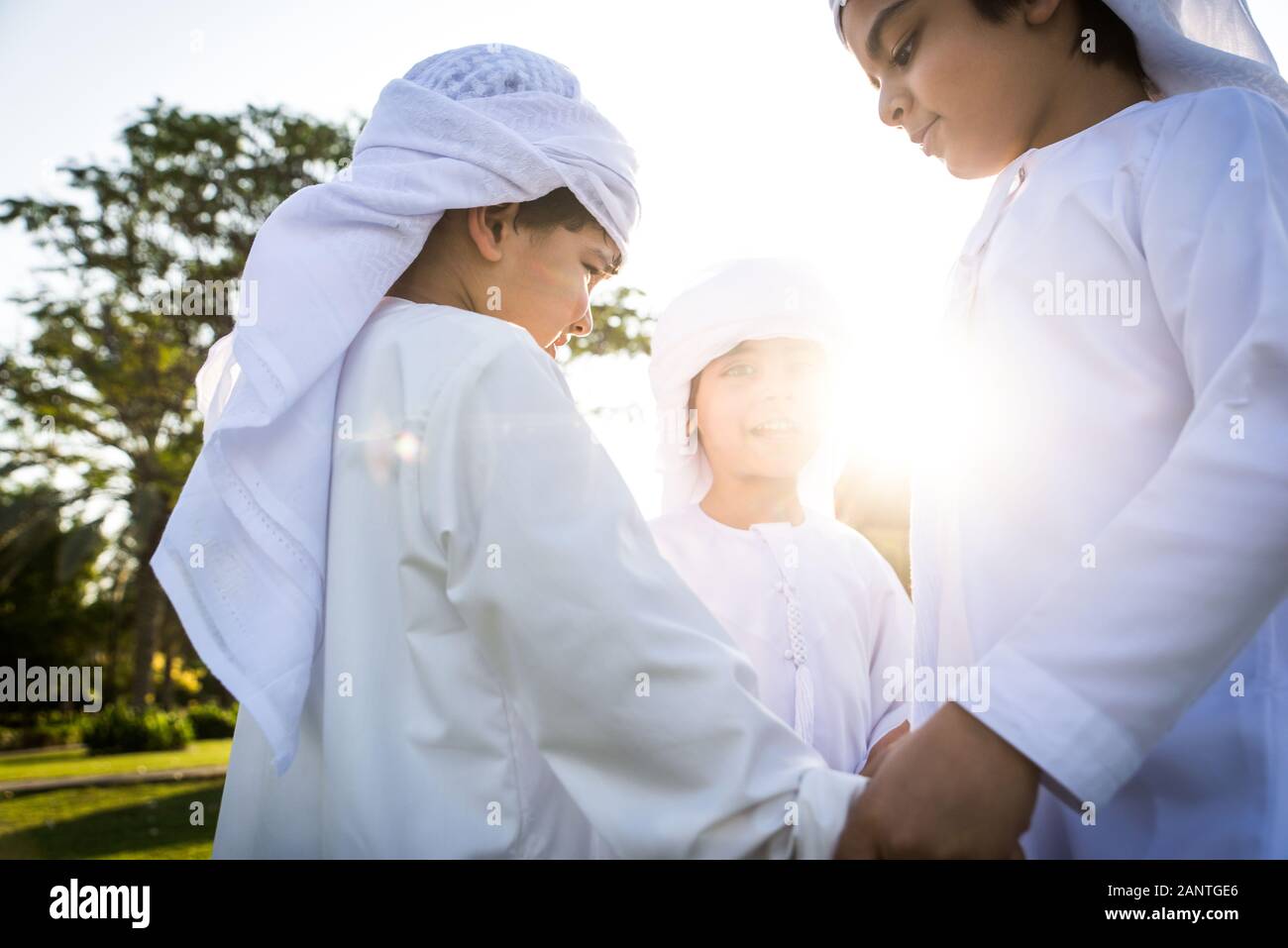Group of middle-eastern kids wearing white kandora playing in a park in ...
