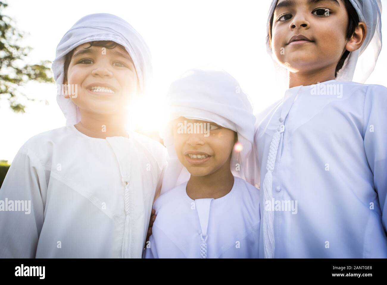 Group of middle-eastern kids wearing white kandora playing in a park in ...