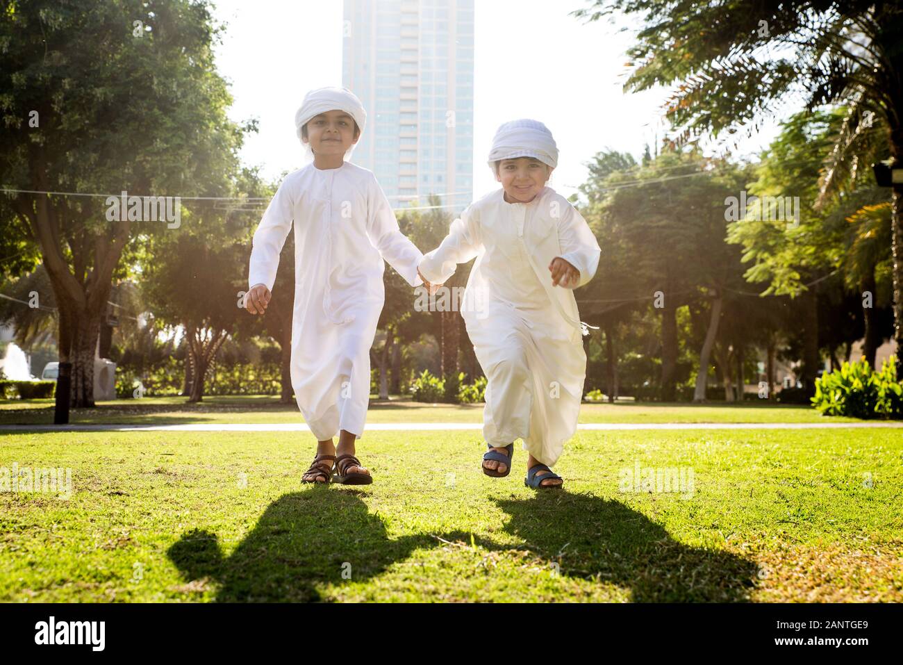 Group of middle-eastern kids wearing white kandora playing in a park in ...